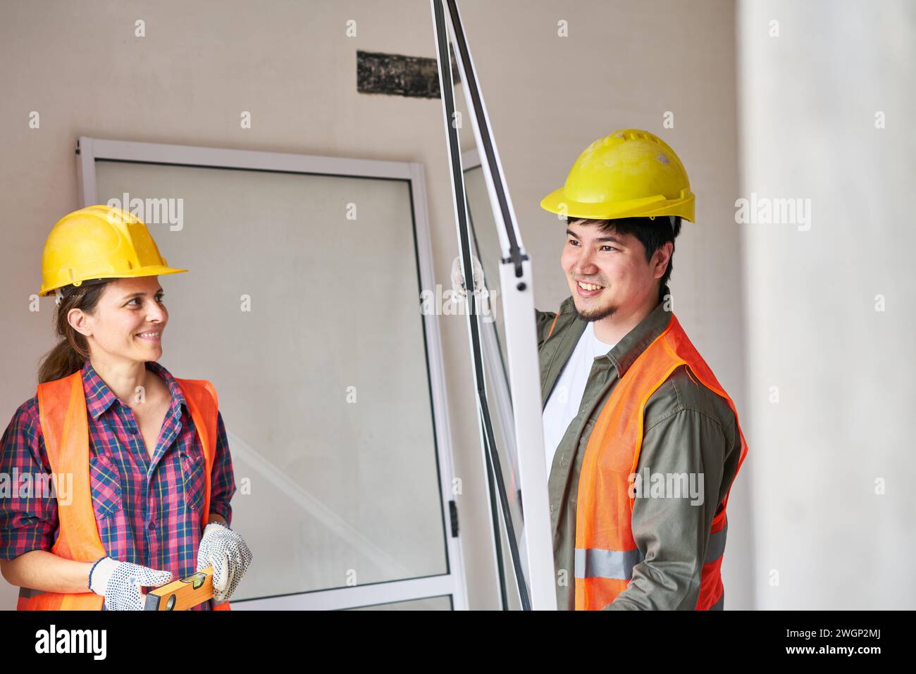 Smiling carpenters installing window frame Stock Photo - Alamy