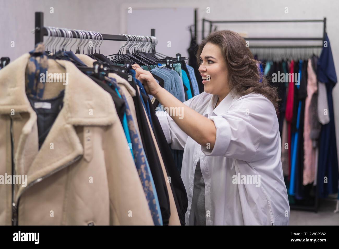 A fat woman in a plus size store chooses clothes while sorting through ...