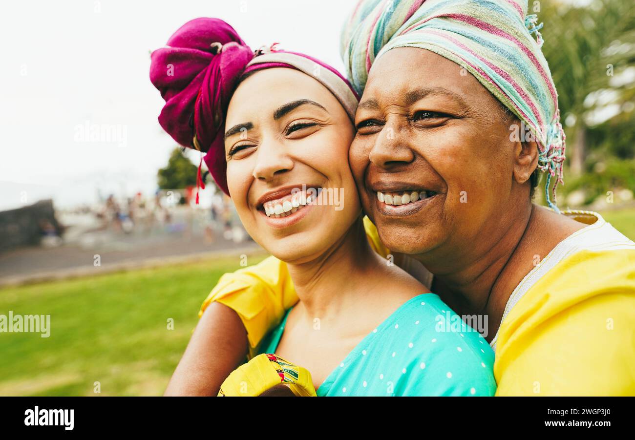 Happy african mother and daughter wearing traditional clothes while having fun together outdoor ...