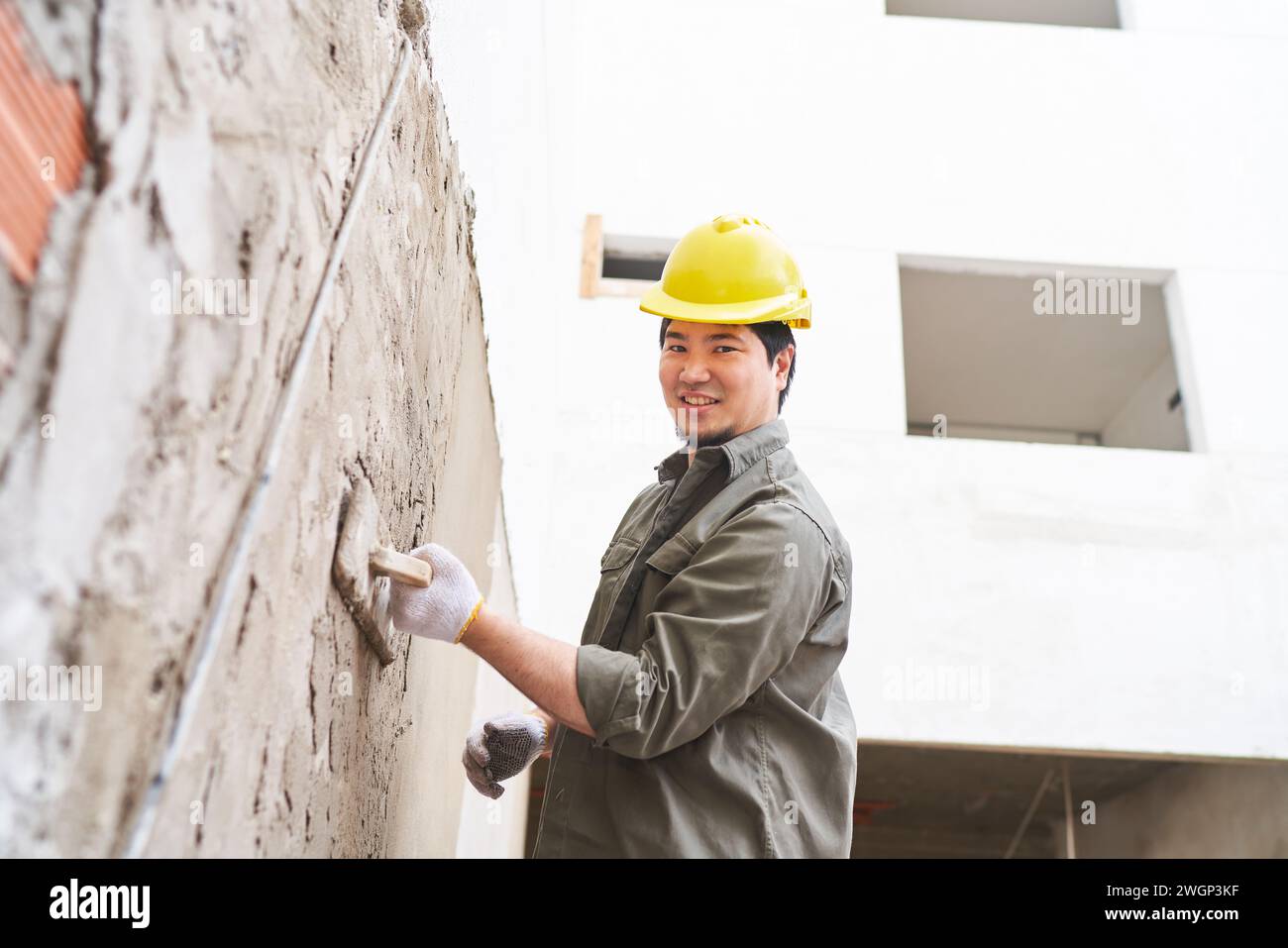 Smiling male labor applying cement on wall Stock Photo - Alamy