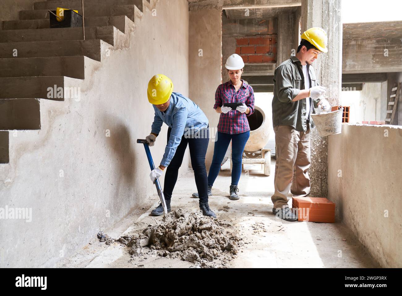 Young multiethnic masons mixing mortar by supervisor Stock Photo - Alamy