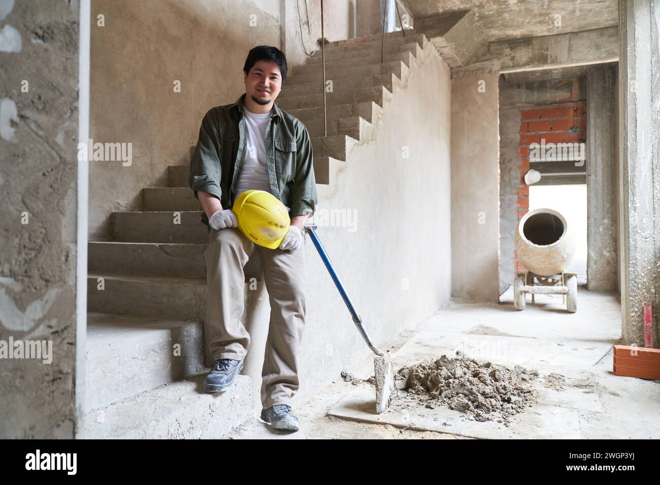 Smiling bricklayer leaning on staircase by cement Stock Photo - Alamy