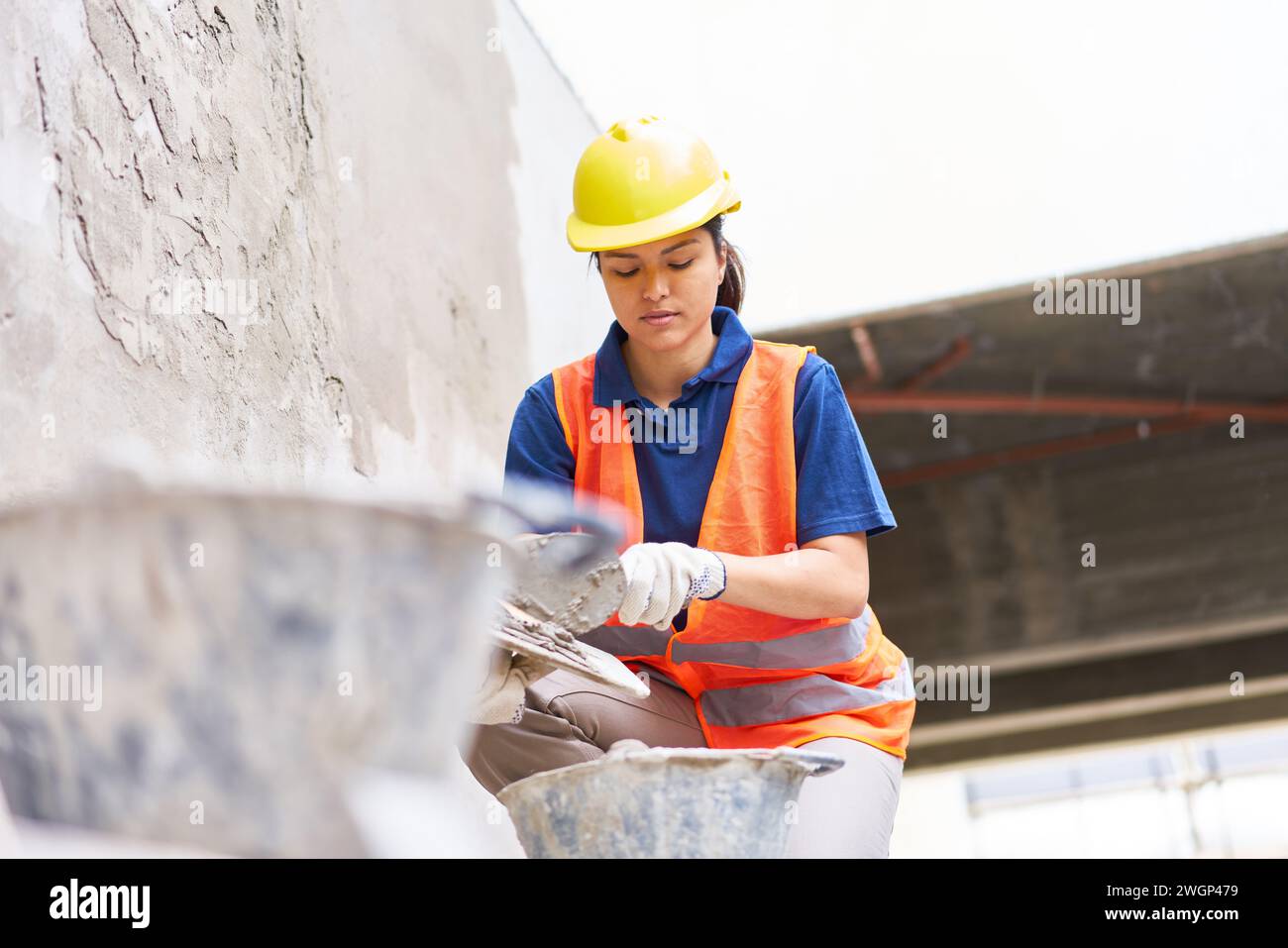 Skilled female bricklayer taking cement from bucket Stock Photo - Alamy