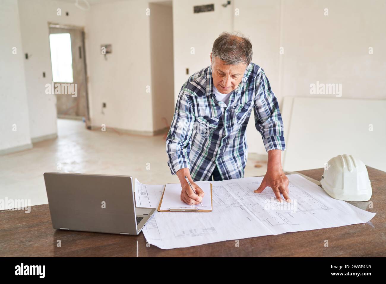 Senior architect writing on clipboard over blueprint Stock Photo - Alamy
