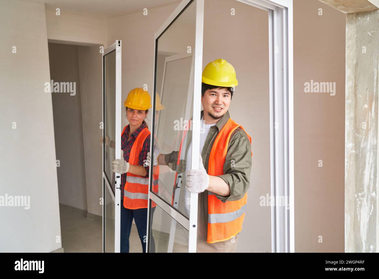 Smiling carpenters carrying window frames Stock Photo - Alamy