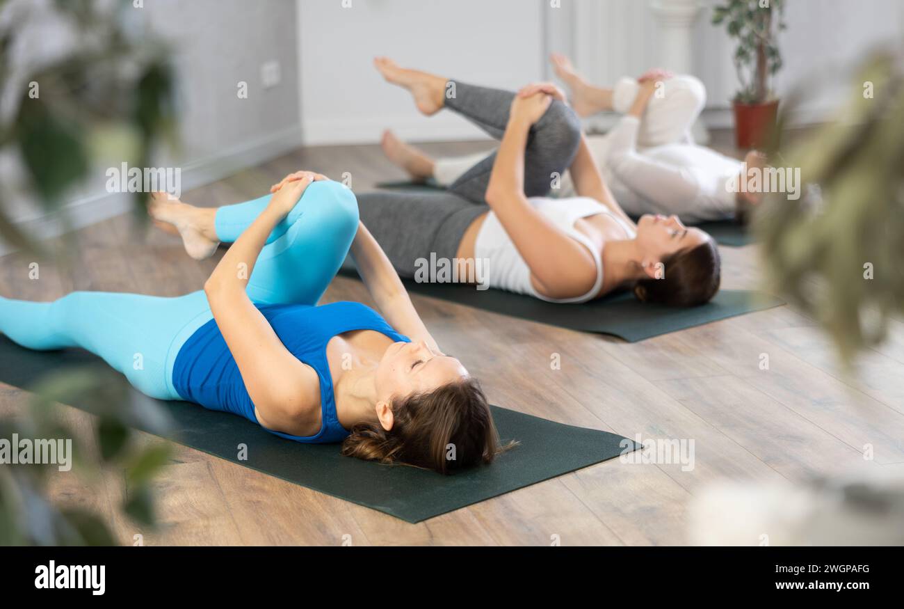 Group of women practice the Pawana Muktasana pose Stock Photo - Alamy