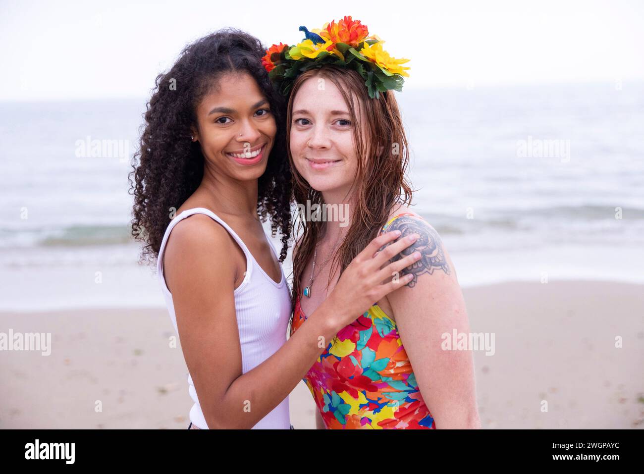 portraits of young mixed race women, friends posing on the beach having ...