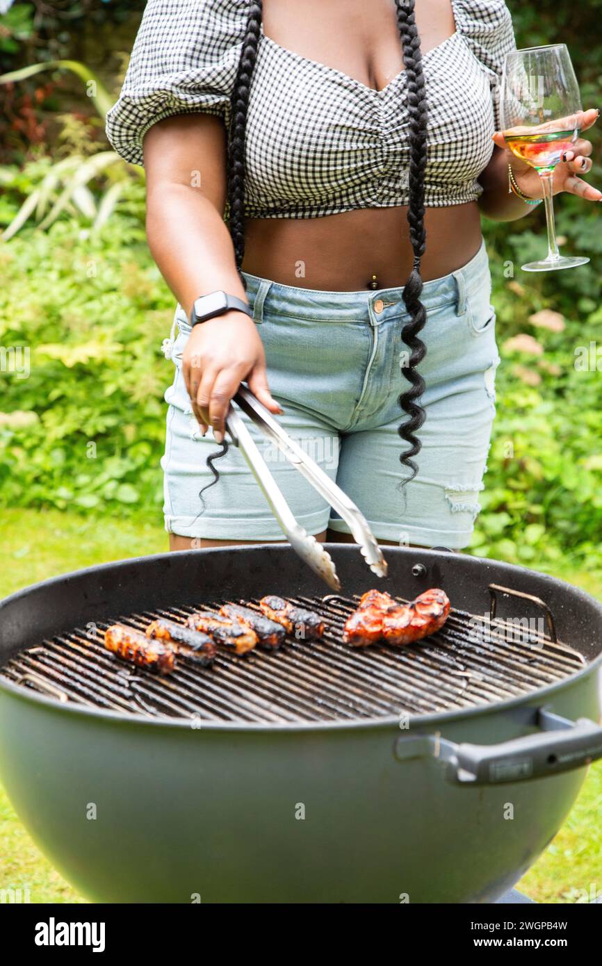 Women enjoying a summer BBQ garden party cooking and eating outside ...