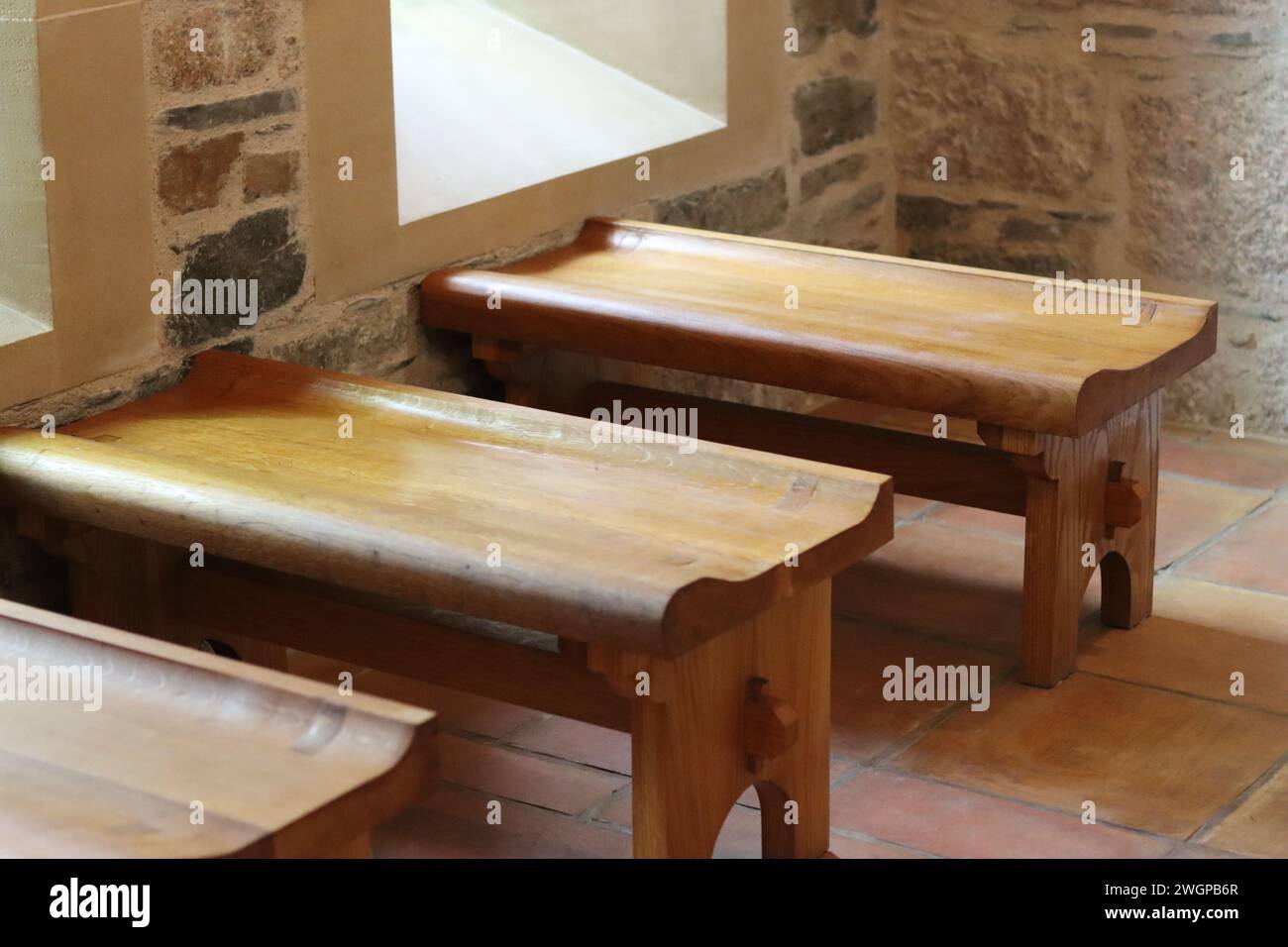 Rows of simple wooden benches in a small stone chapel Stock Photo - Alamy