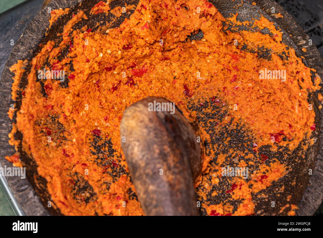 Close up of Spicy spices are grinded using traditional tools. Mortar ...