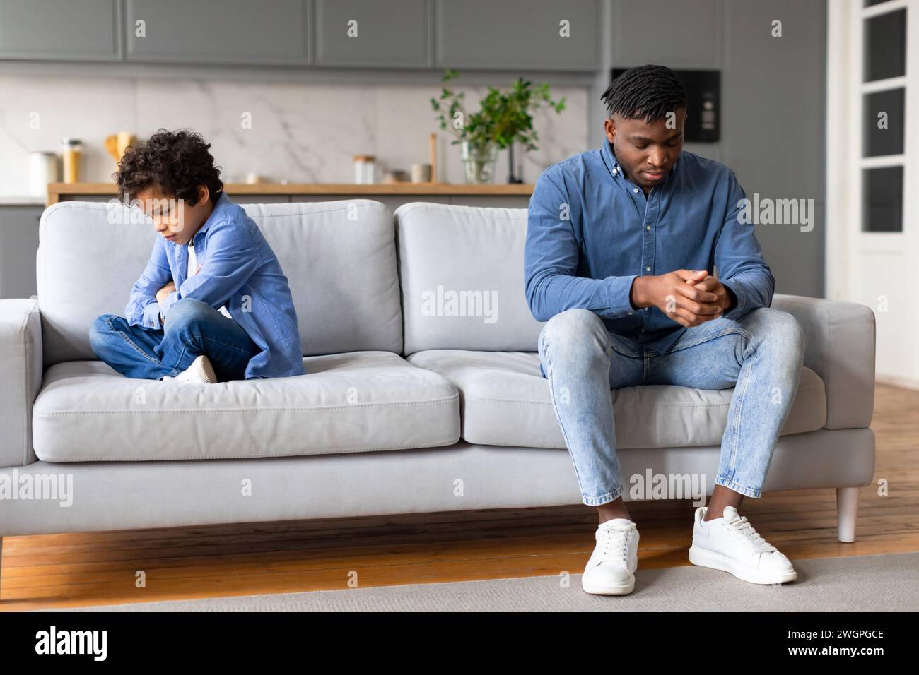 Upset black father and son sitting apart on couch, having disagreement ...