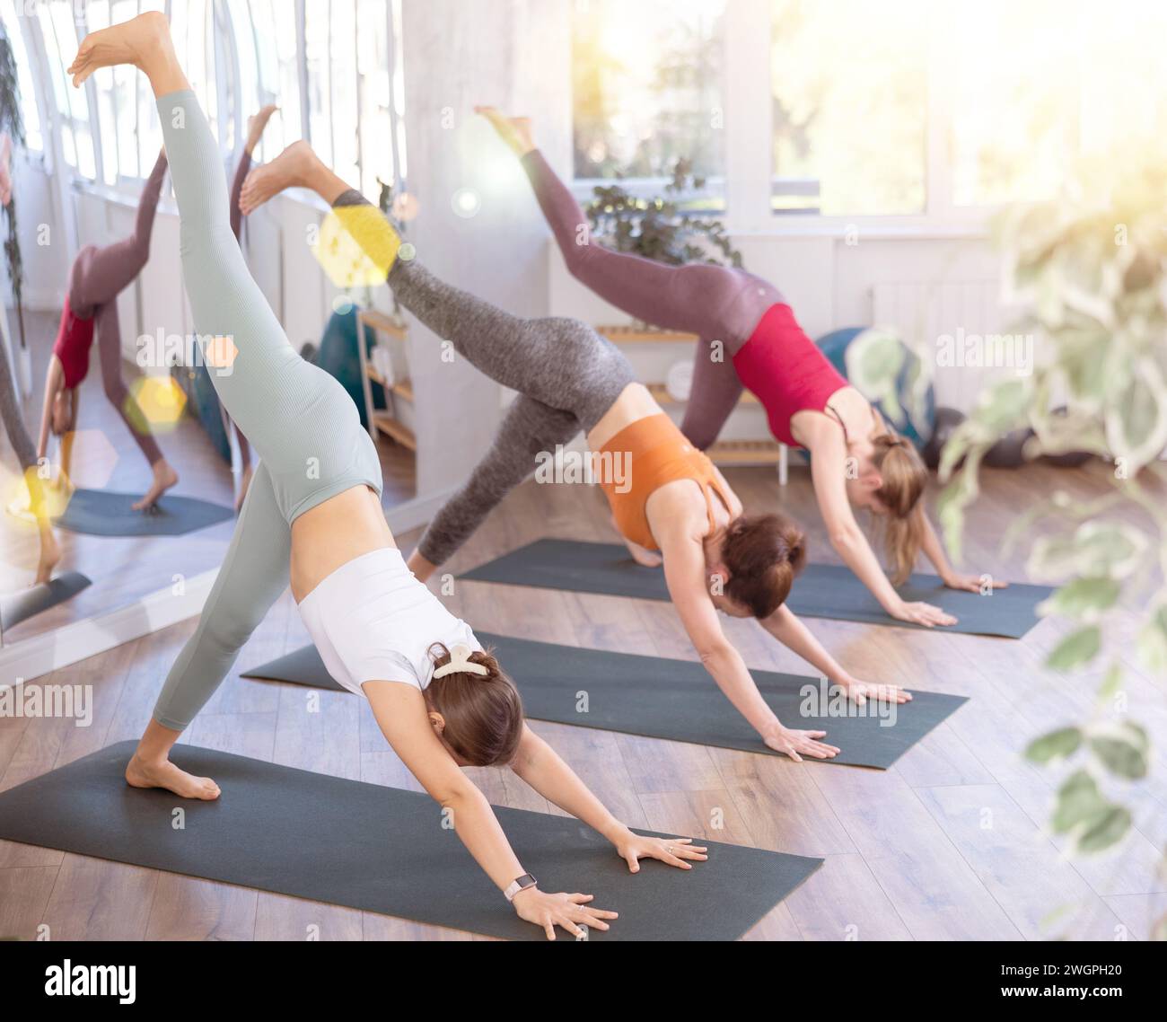 Women demonstrating forward bend pose of yoga in training room Stock ...