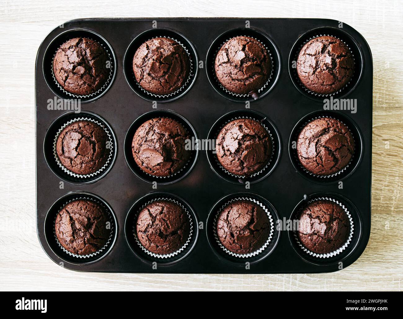 Above view of small baked chocolate muffins inside muffin pan indoors ...