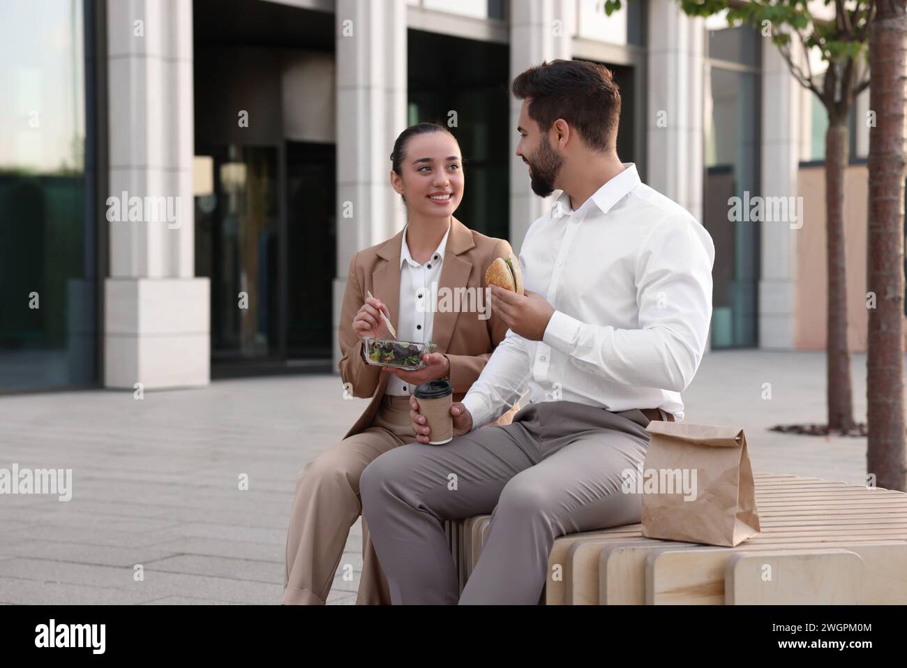 Happy colleagues having business lunch together on bench outdoors Stock ...