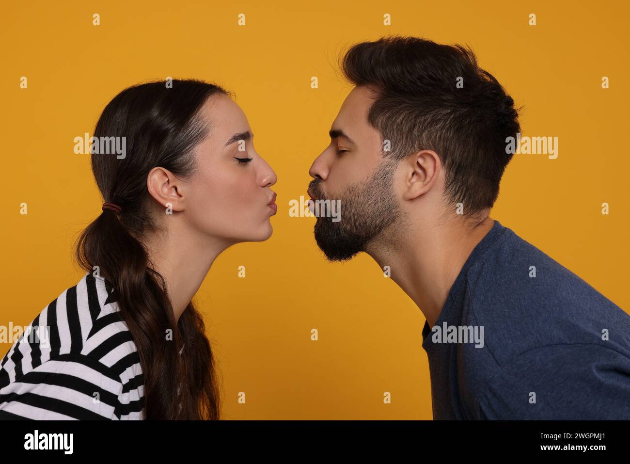 Cute young couple kissing on orange background Stock Photo - Alamy