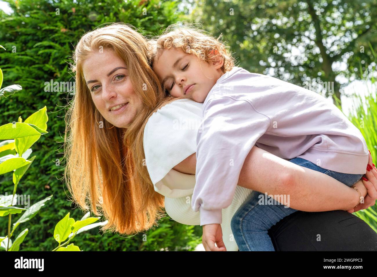Mother carrying tired son into their home Stock Photo - Alamy