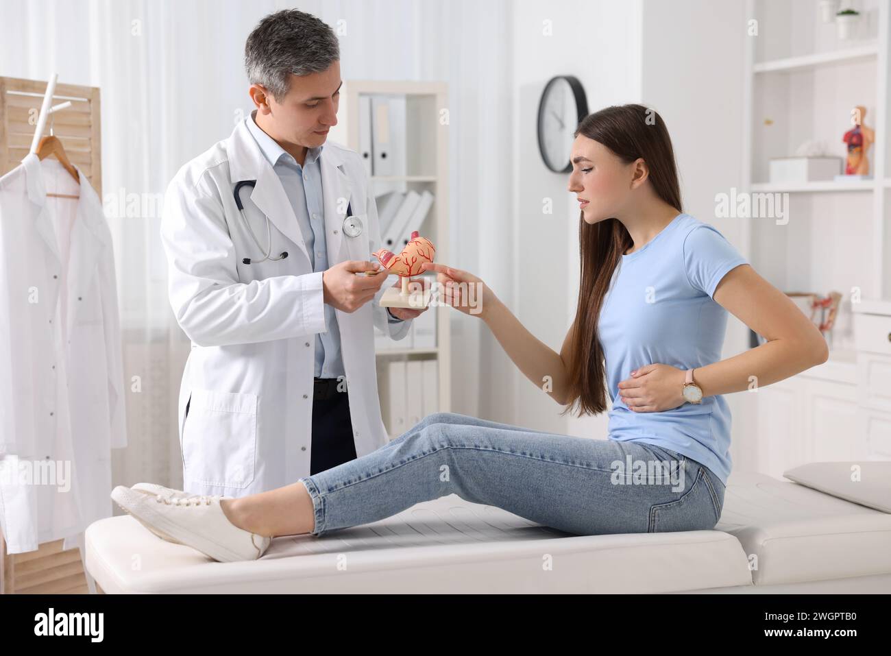Gastroenterologist with human stomach model consulting patient in ...