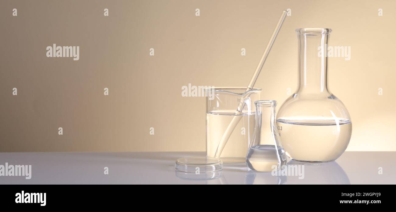 Laboratory analysis. Different glassware on table against beige ...