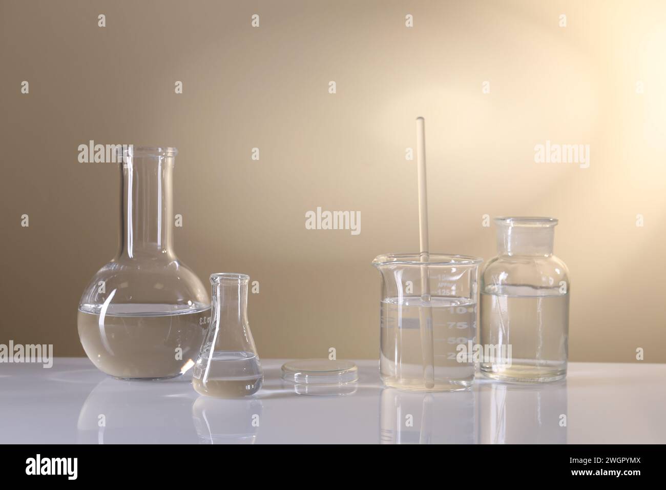 Laboratory analysis. Different glassware on table against beige ...