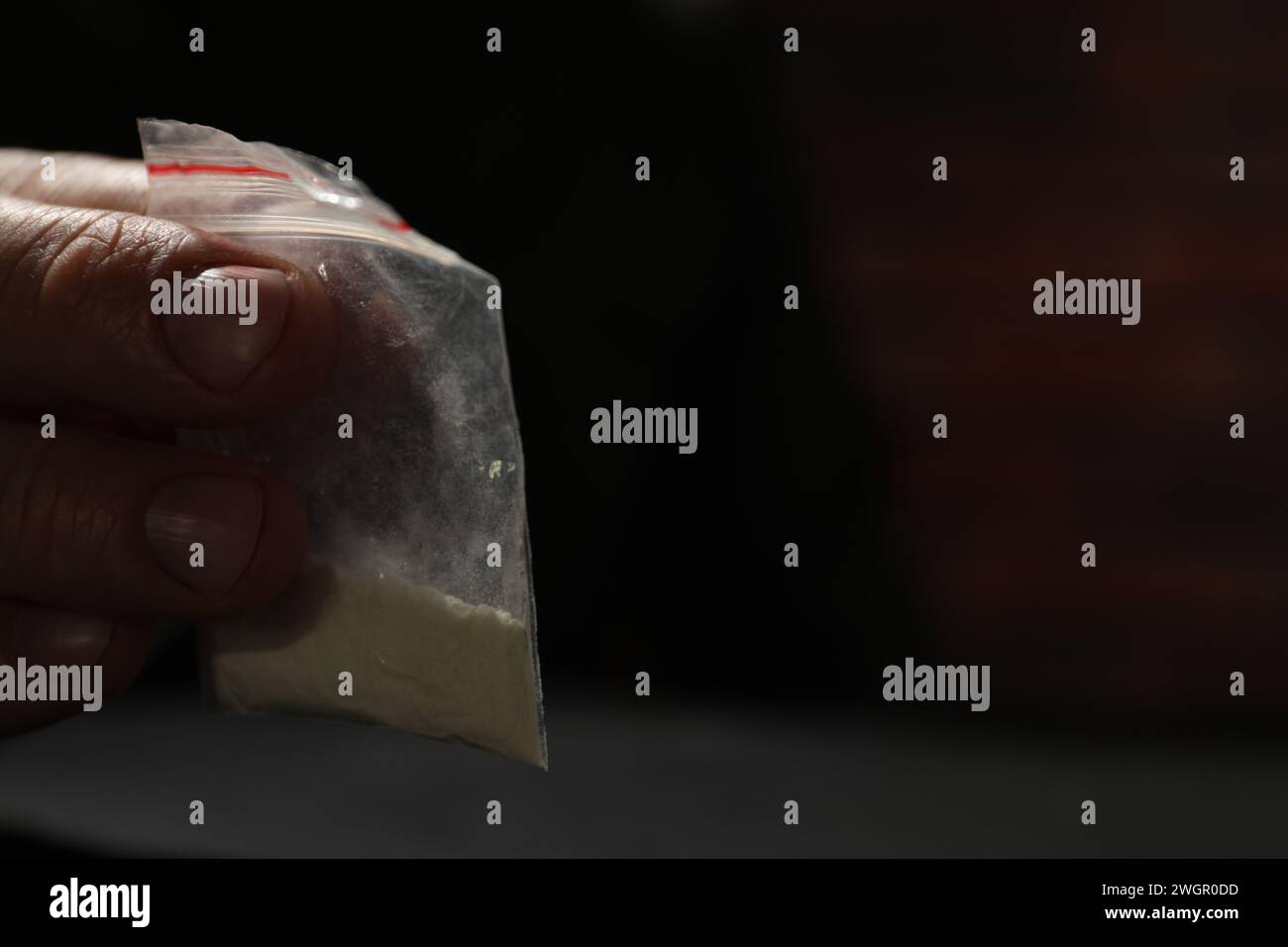 Addicted man with plastic bag of hard drug on blurred background ...