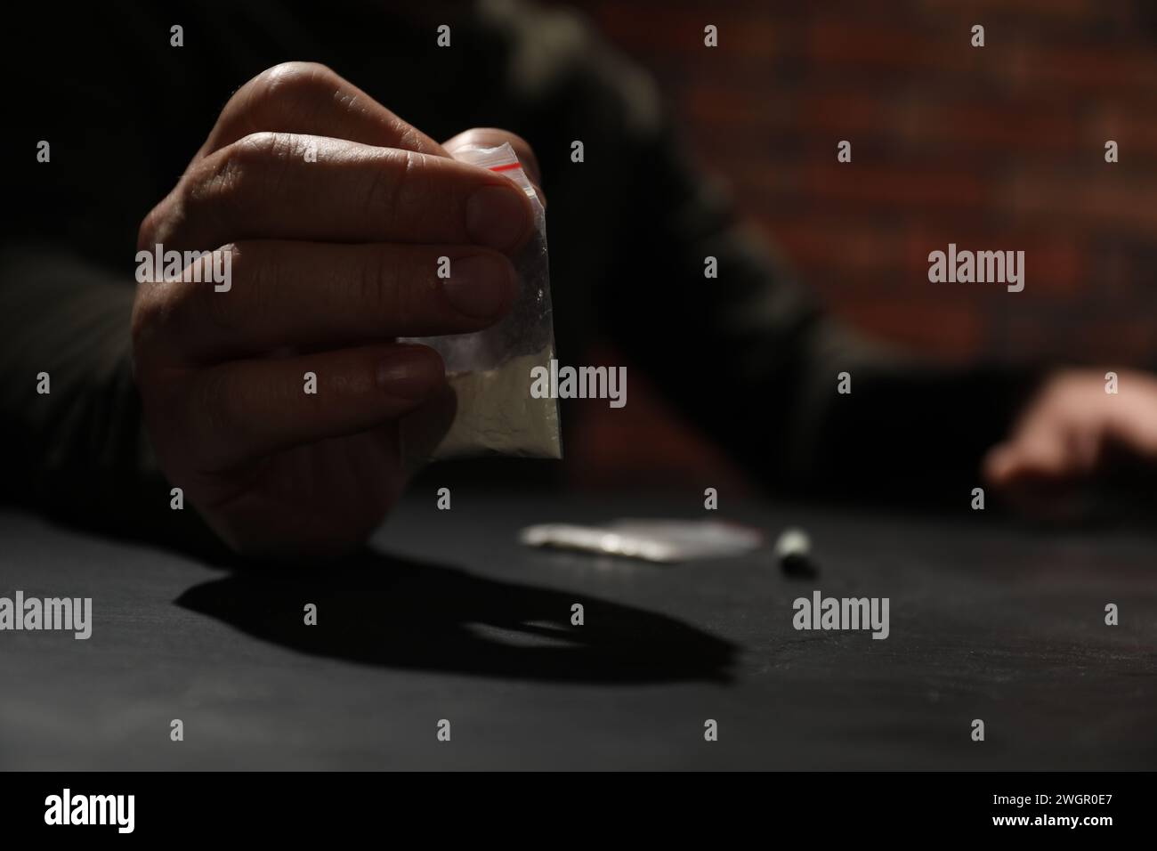 Drug addiction. Man with plastic bag of cocaine at grey table ...