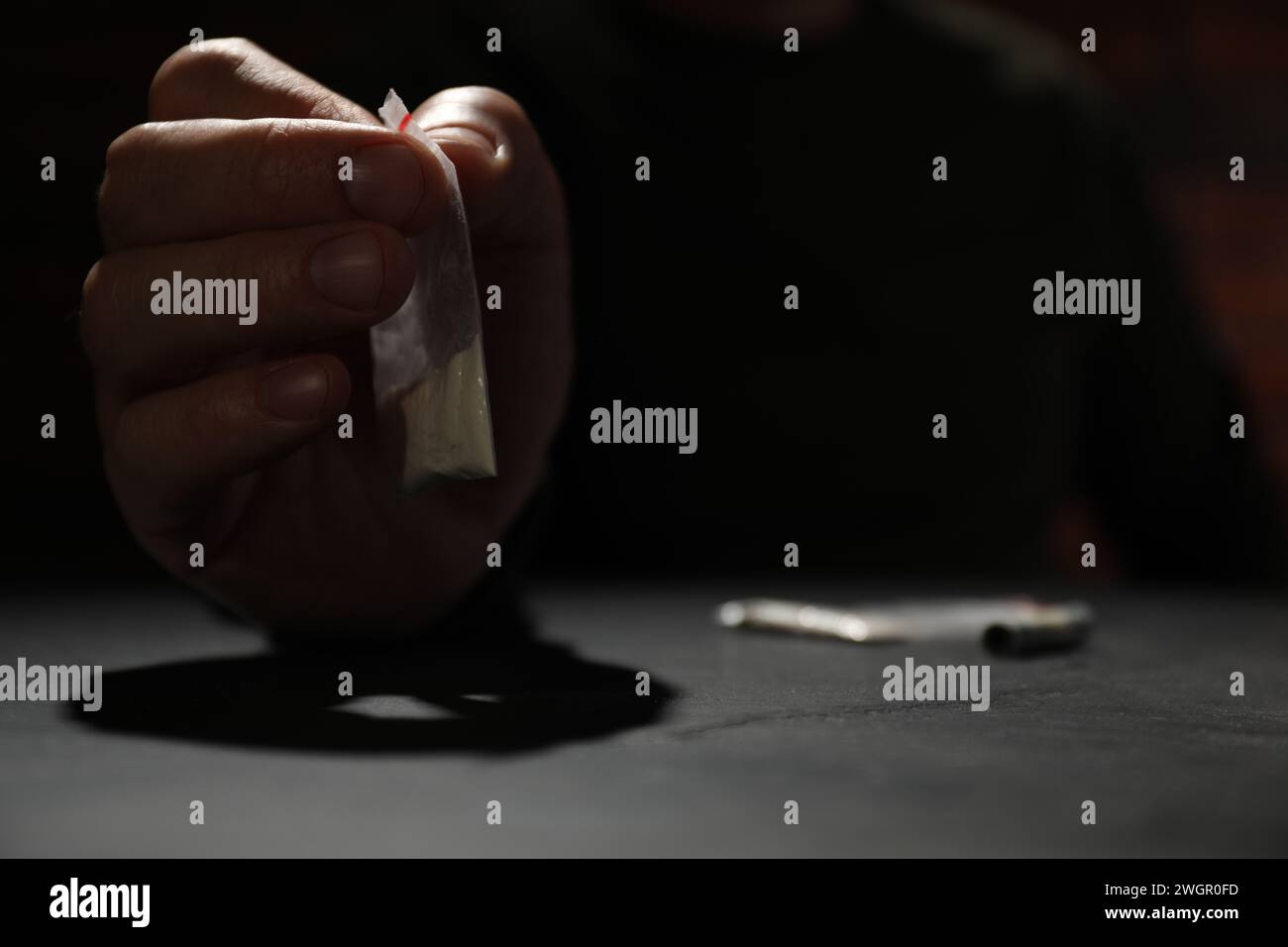 Drug addiction. Man with plastic bag of cocaine at grey table ...
