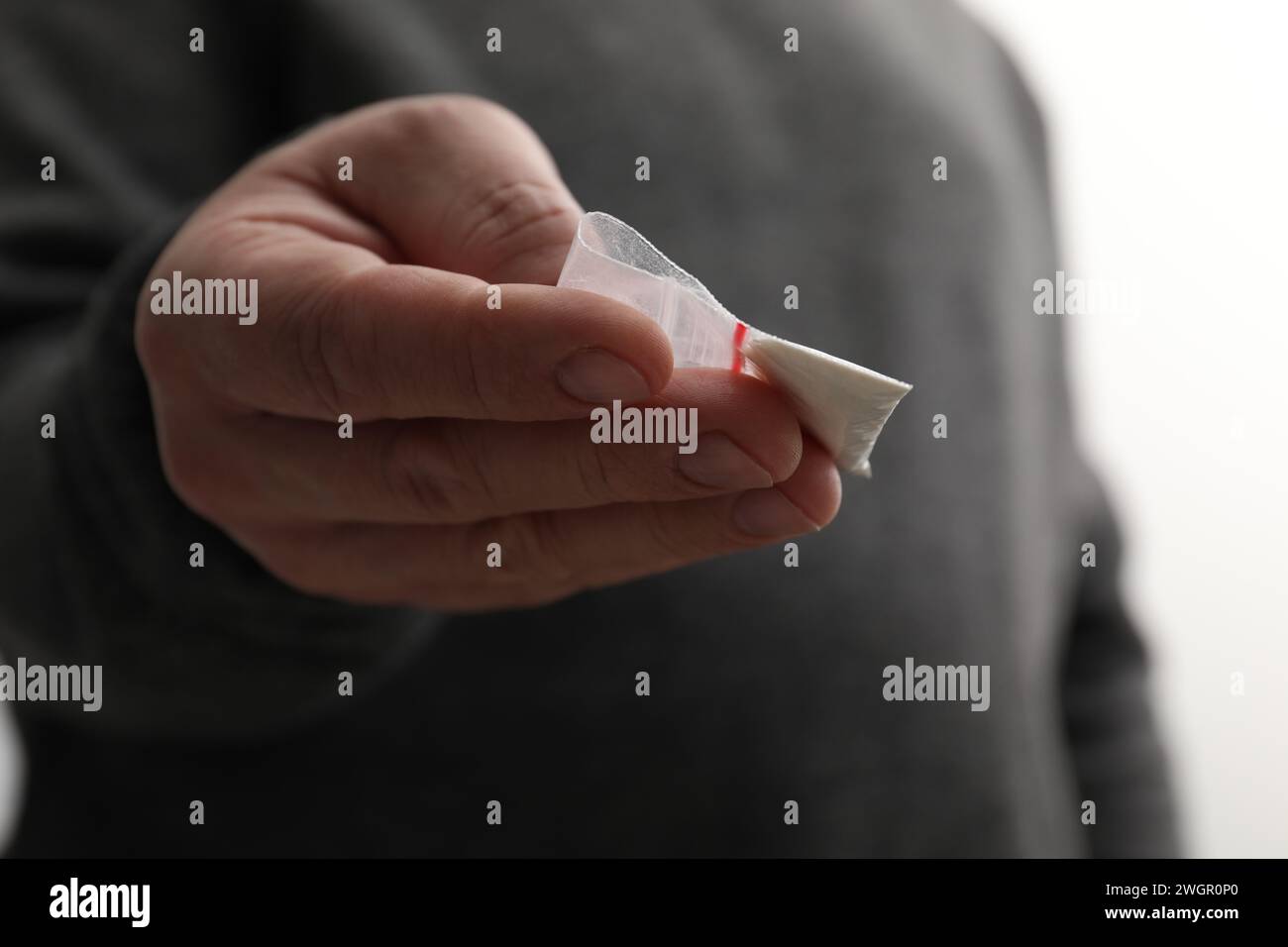 Drug addiction. Man with plastic bag of cocaine on light background ...