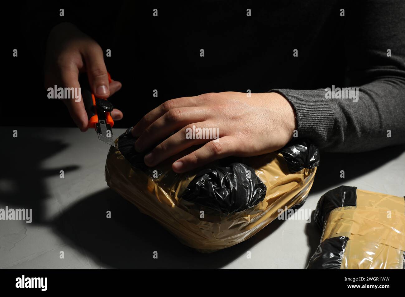 Smuggling and drug trafficking. Man opening package of narcotics with ...