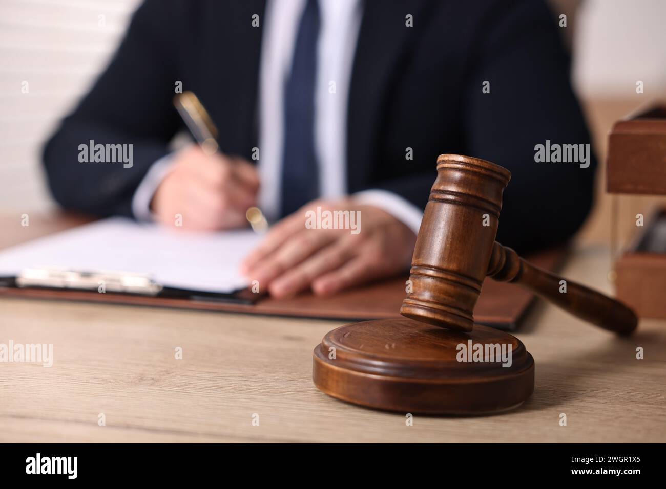 Notary writing notes at wooden table in office, focus on gavel Stock ...