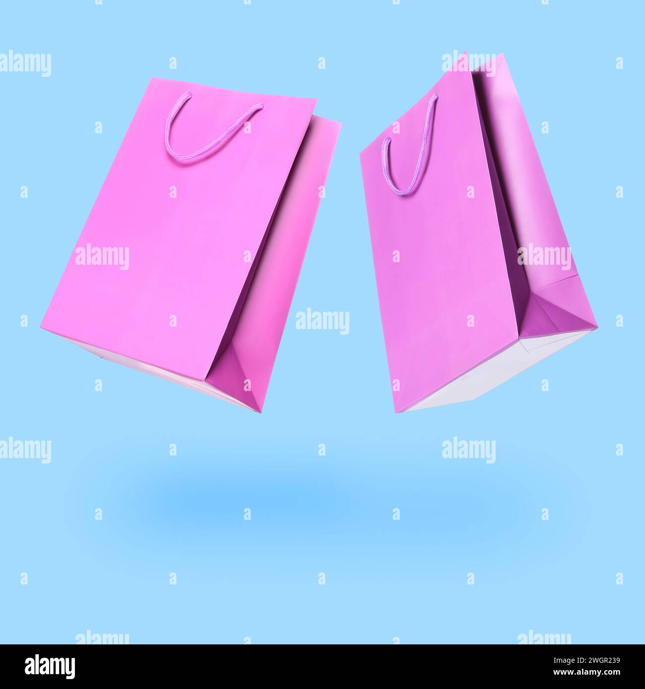 Magenta shopping bags falling on light blue background Stock Photo - Alamy