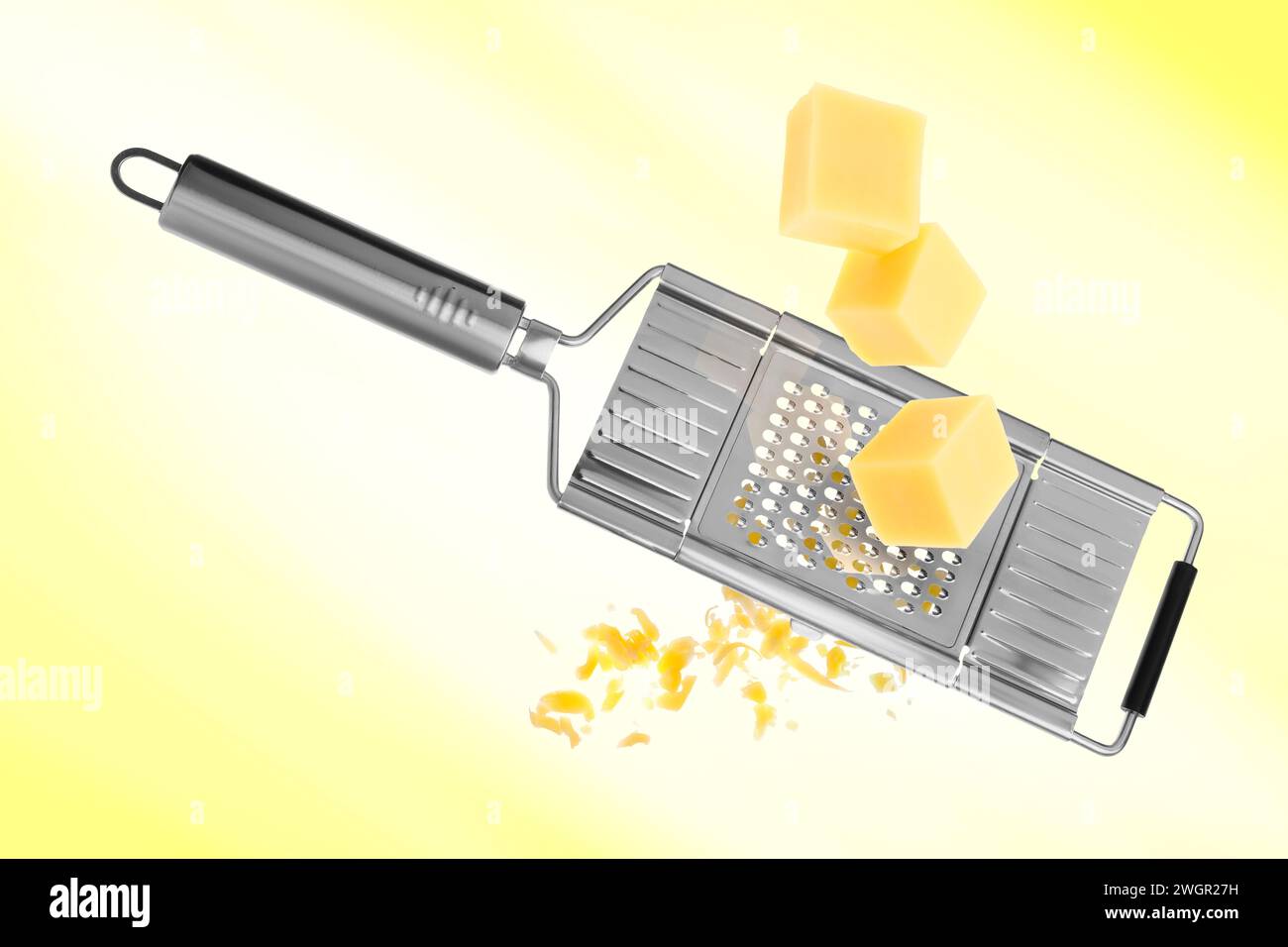 Grating cheese with hand grater on yellow background Stock Photo - Alamy