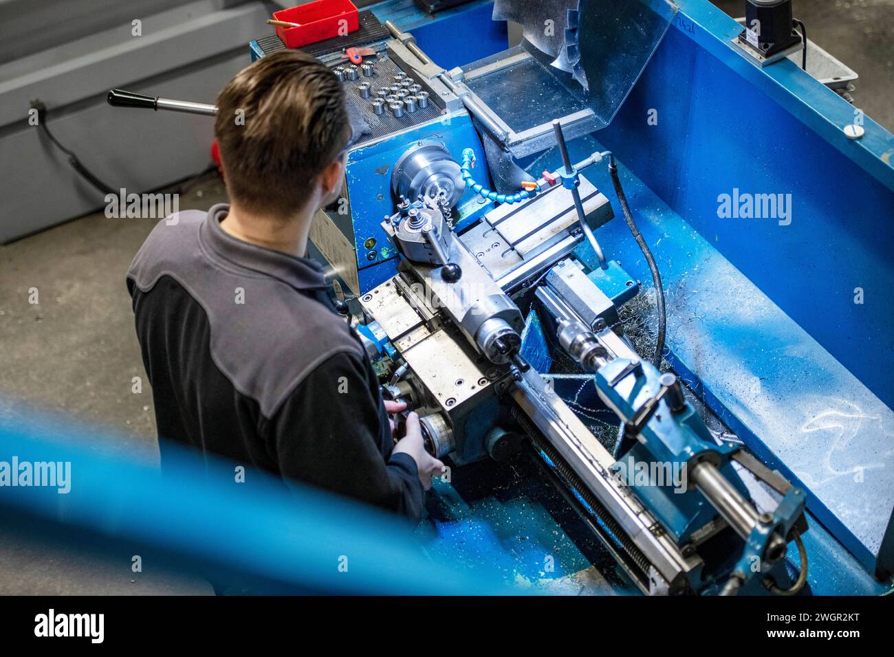 Young mechanical engineer working on steel machinery in a factory lathe ...