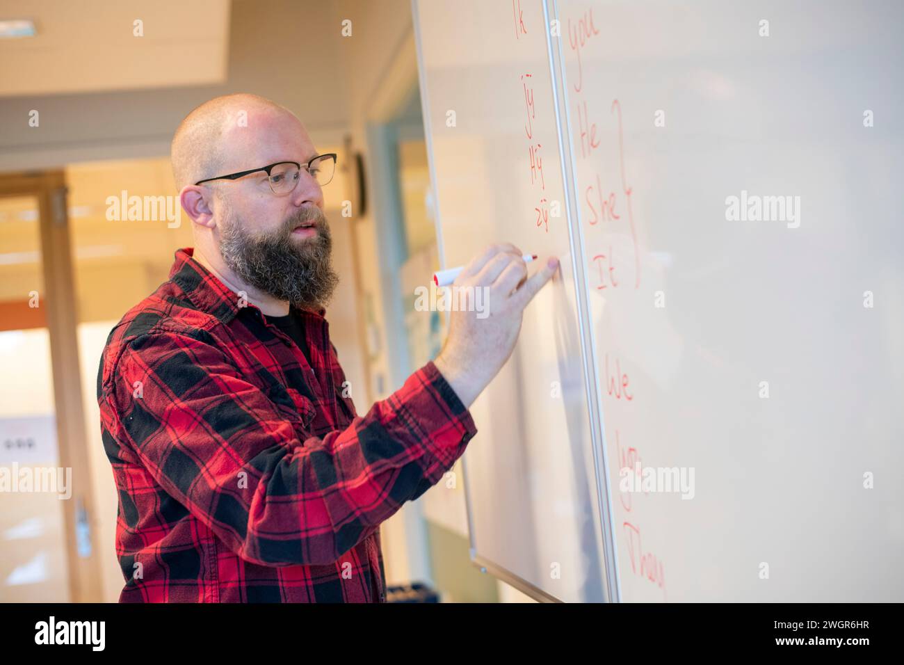 Teacher in class writing on white board with a marker Stock Photo - Alamy