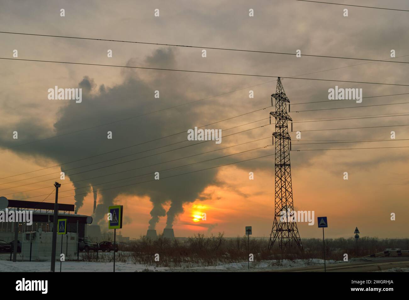 High power line and wires against the backdrop of sunset and smoke from ...