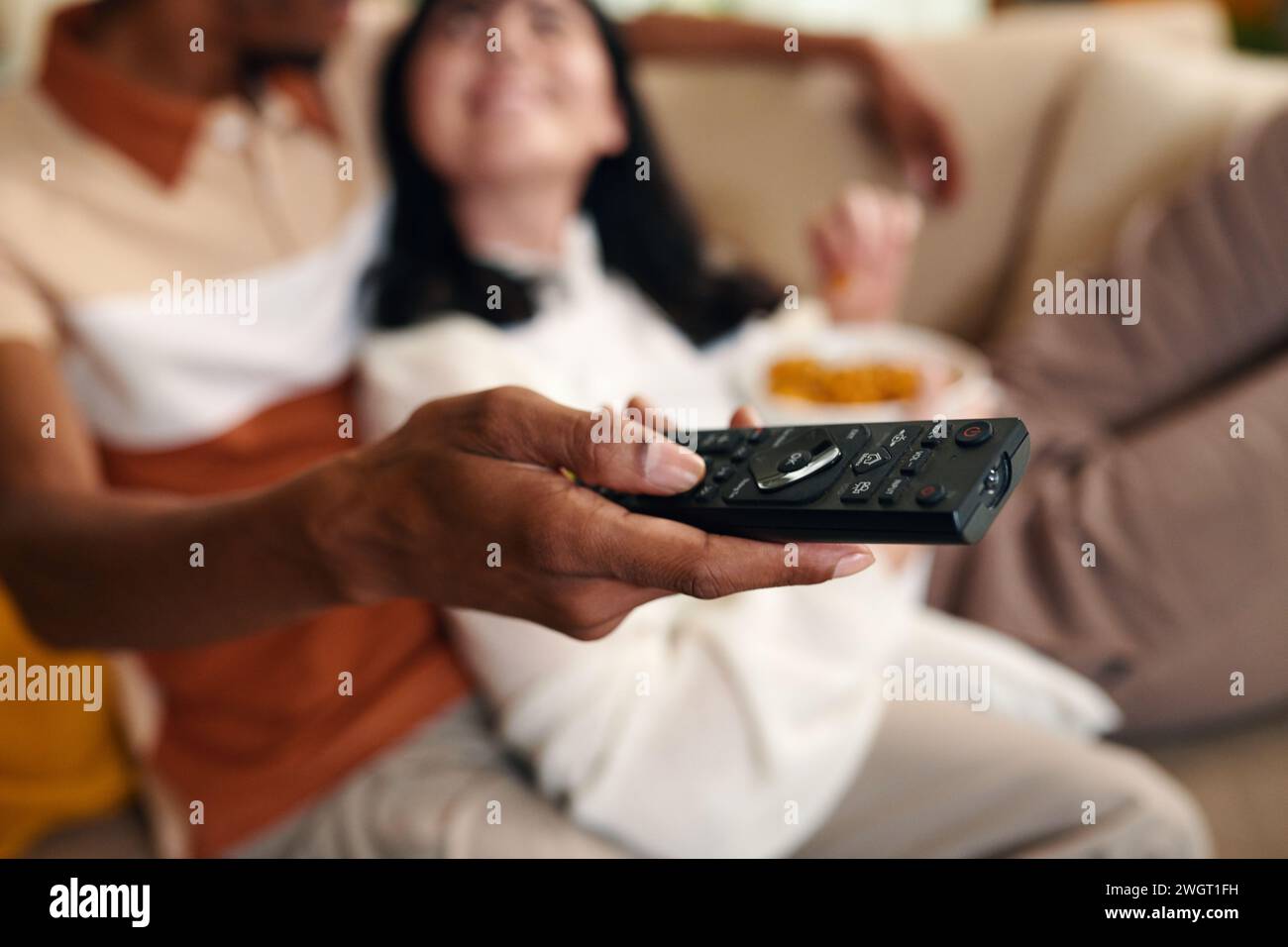 Hand of young African American man with remote control choosing channel ...