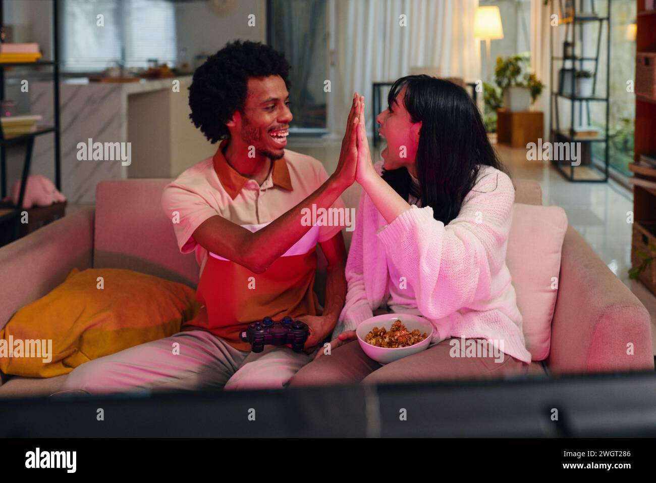 Excited intercultural fans giving each other high five while ...