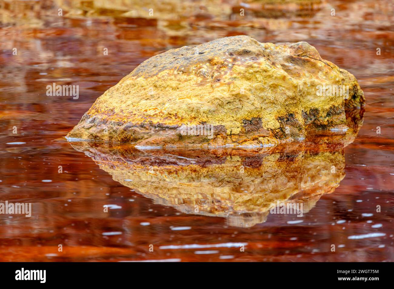 A solitary golden rock casts its reflection upon the tranquil, iron ...
