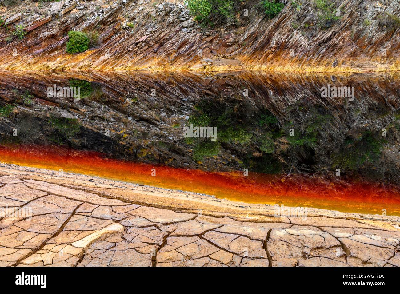 Striking layers of earth and a vivid streak of red water line the ...