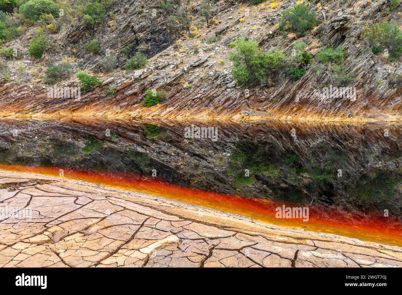 Striking layers of earth and a vivid streak of red water line the ...