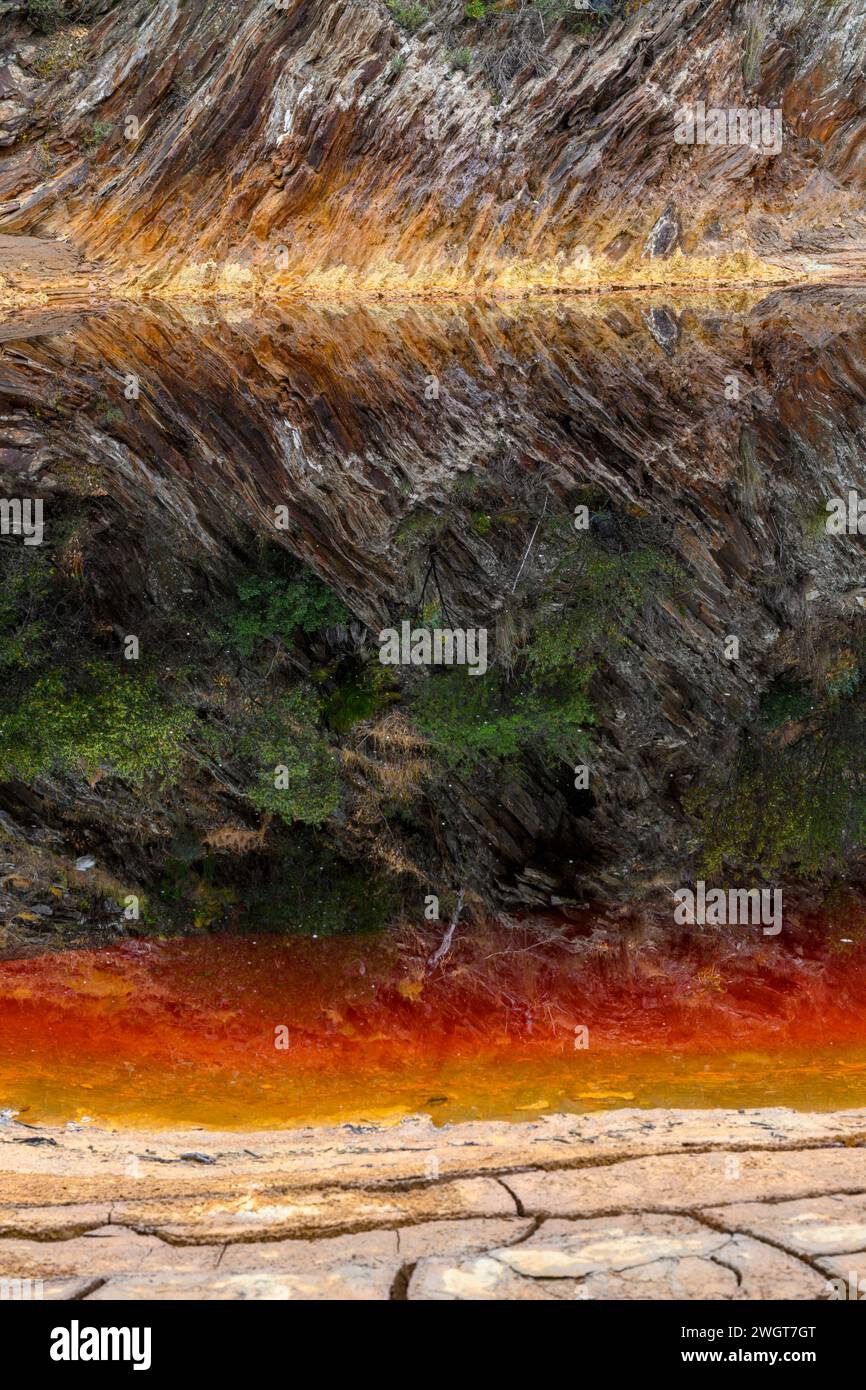 Striking layers of earth and a vivid streak of red water line the ...