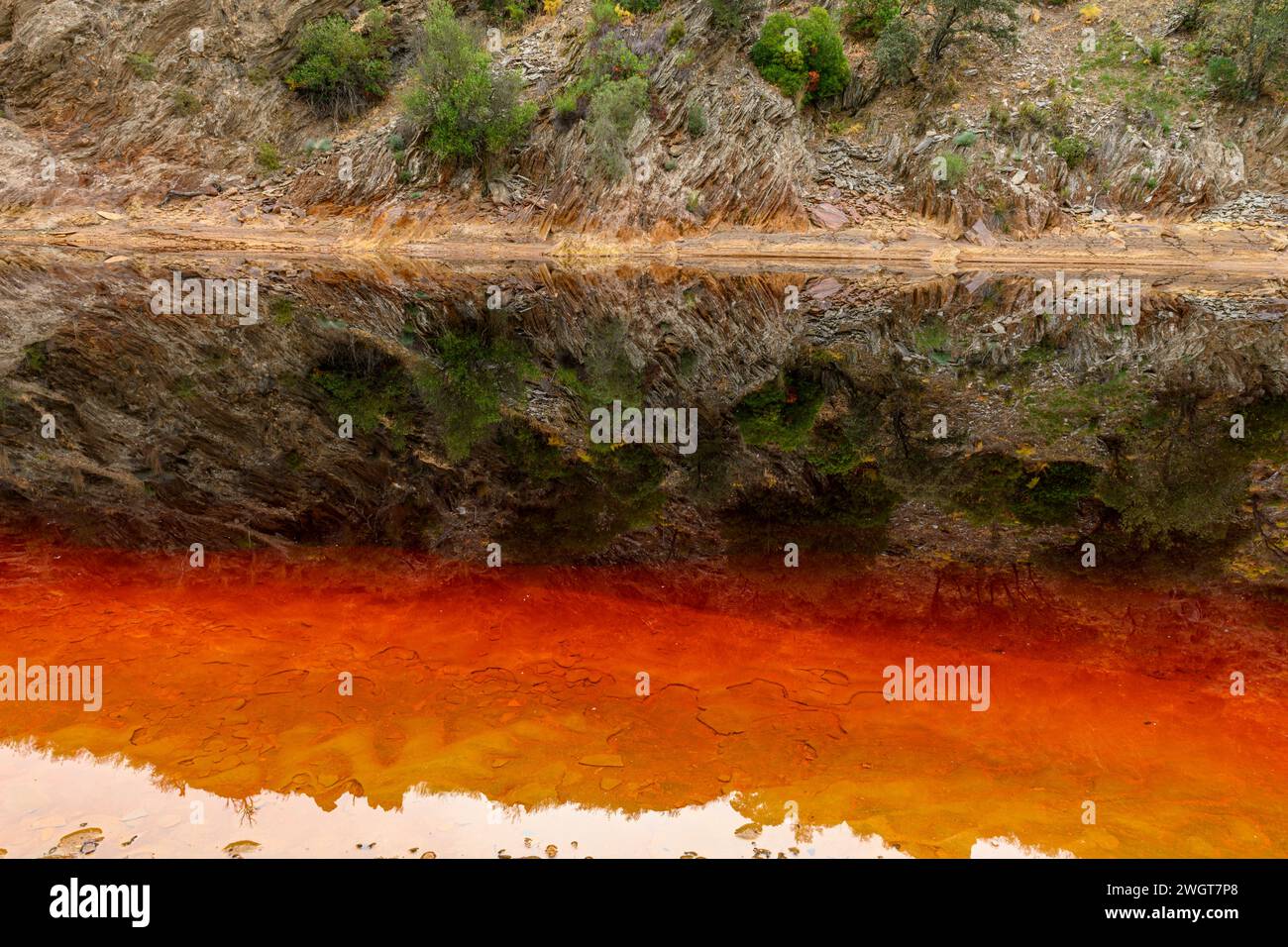 Striking layers of earth and a vivid streak of red water line the ...