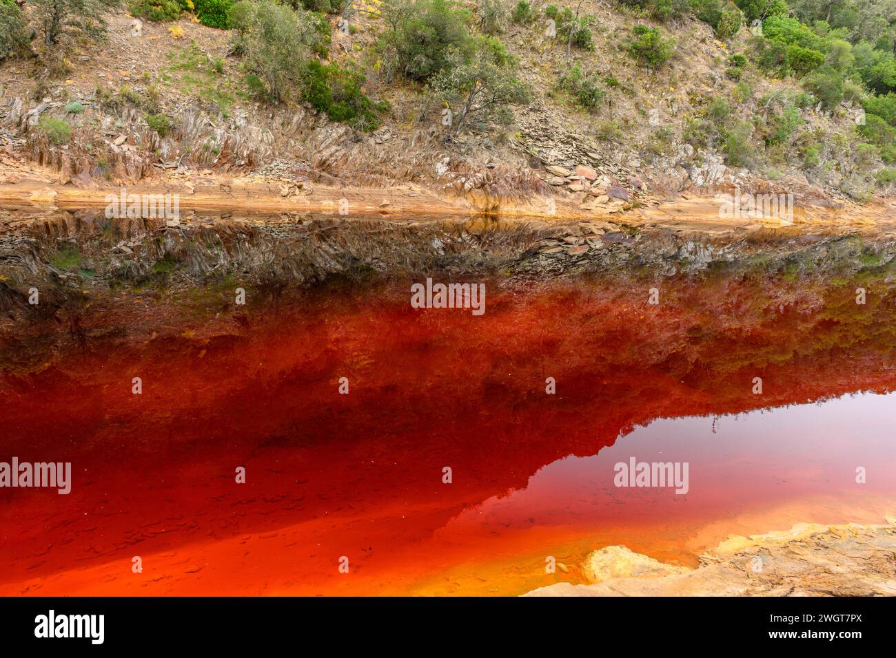 Striking layers of earth and a vivid streak of red water line the ...