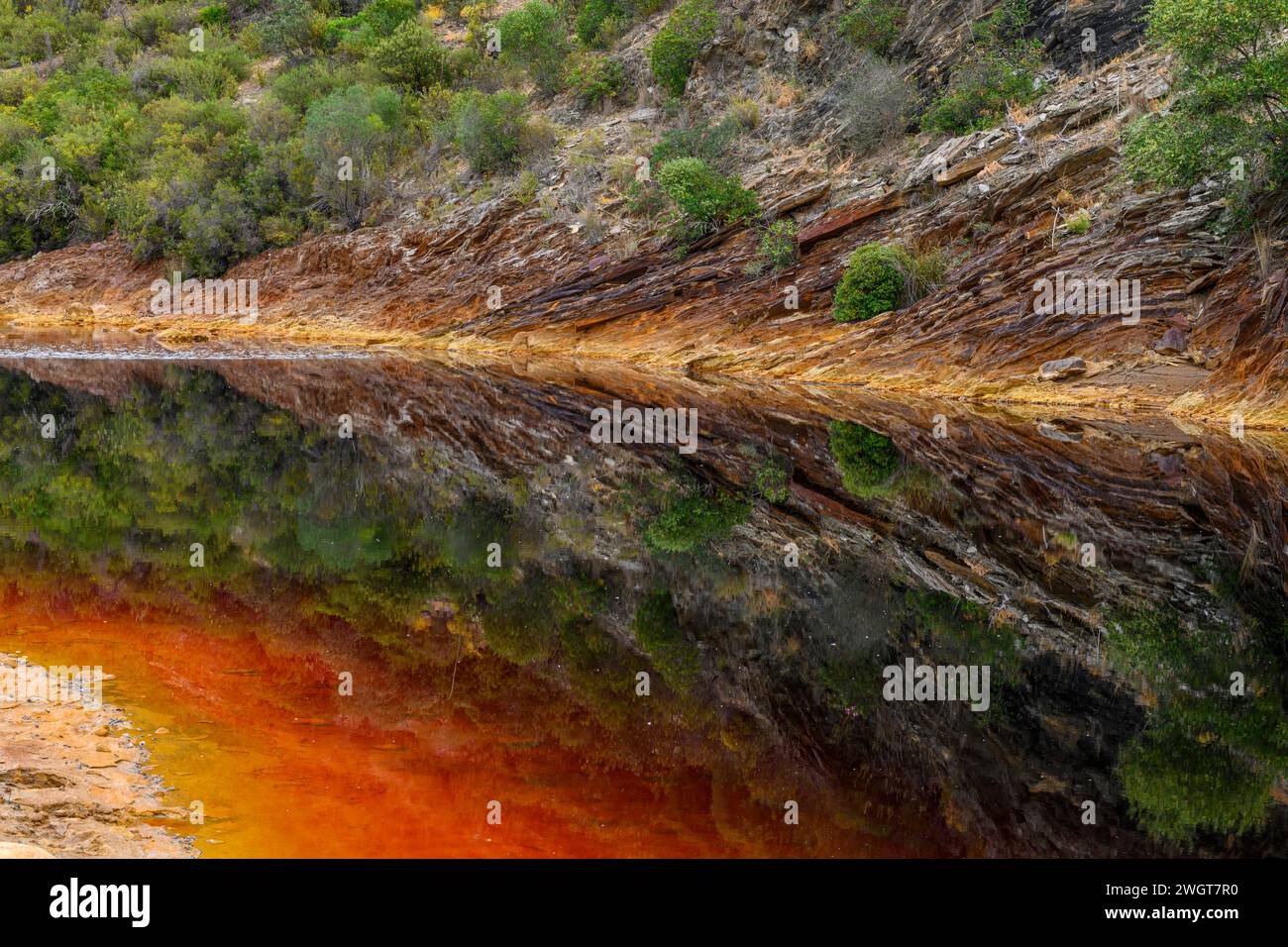 Striking layers of earth and a vivid streak of red water line the ...