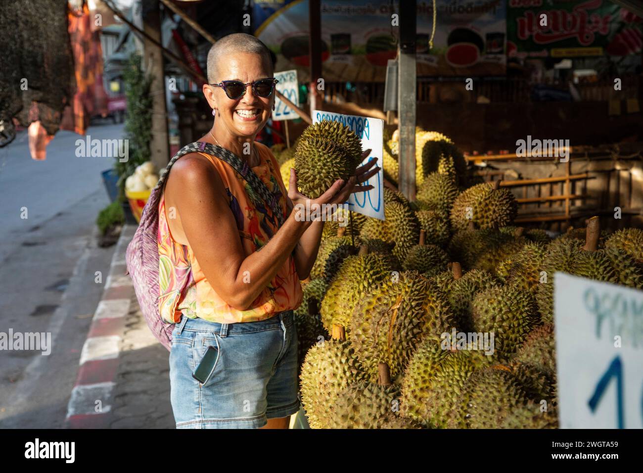 Mid aged woman solo traveller is looking at the local fruit and ...