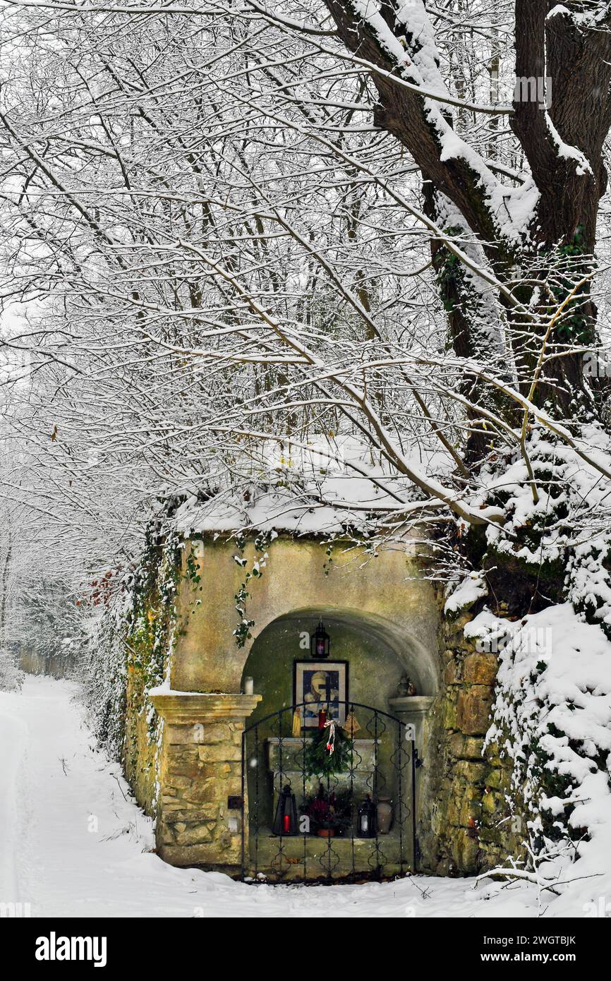 Austria, wayside shrine in deep snow-covered deciduous forest of the ...