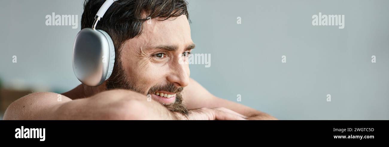 merry man with beard and headphones sitting and relaxing in his bathtub ...