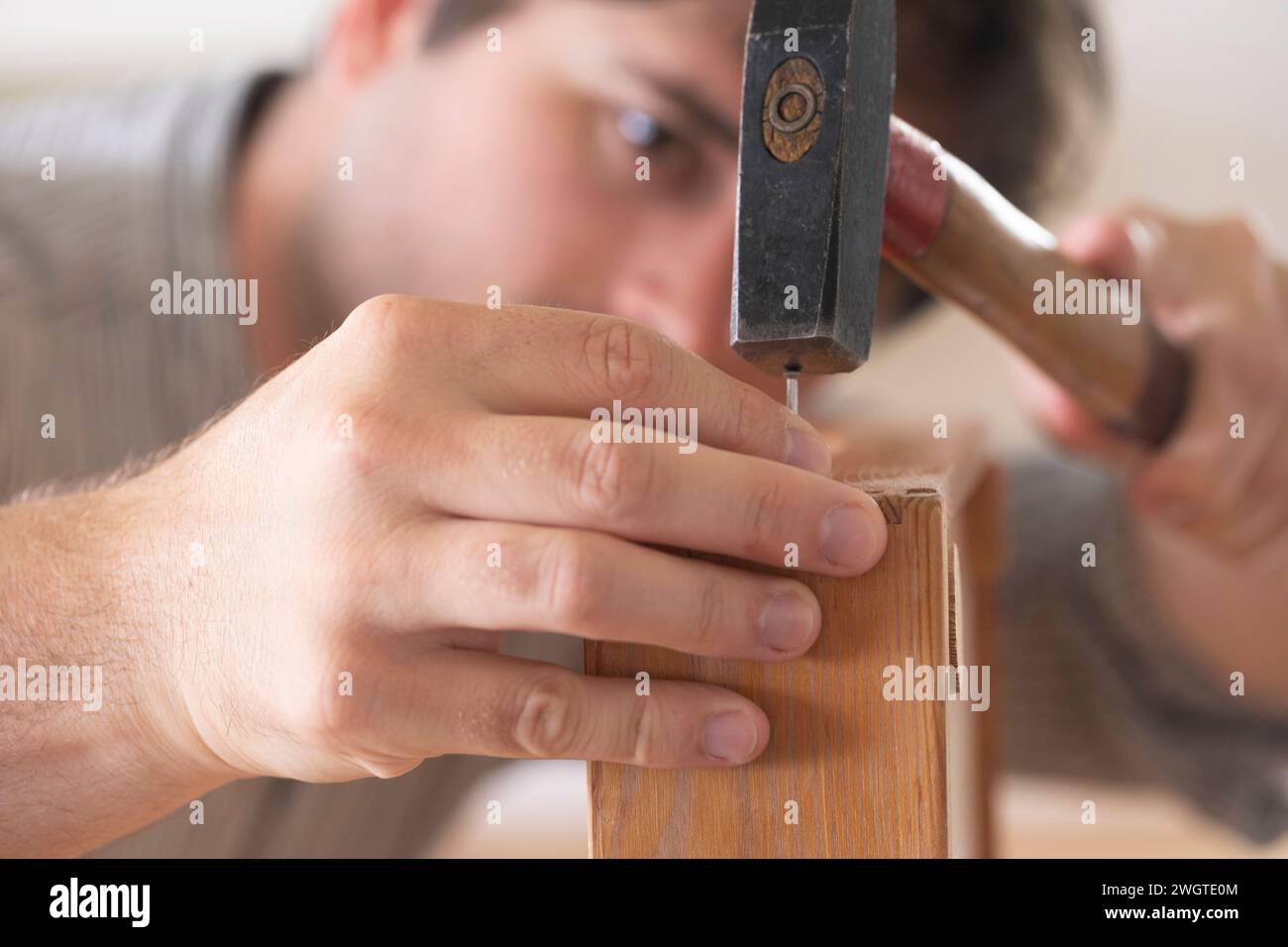 young man knocking with hammer to a wood stick Stock Photo - Alamy