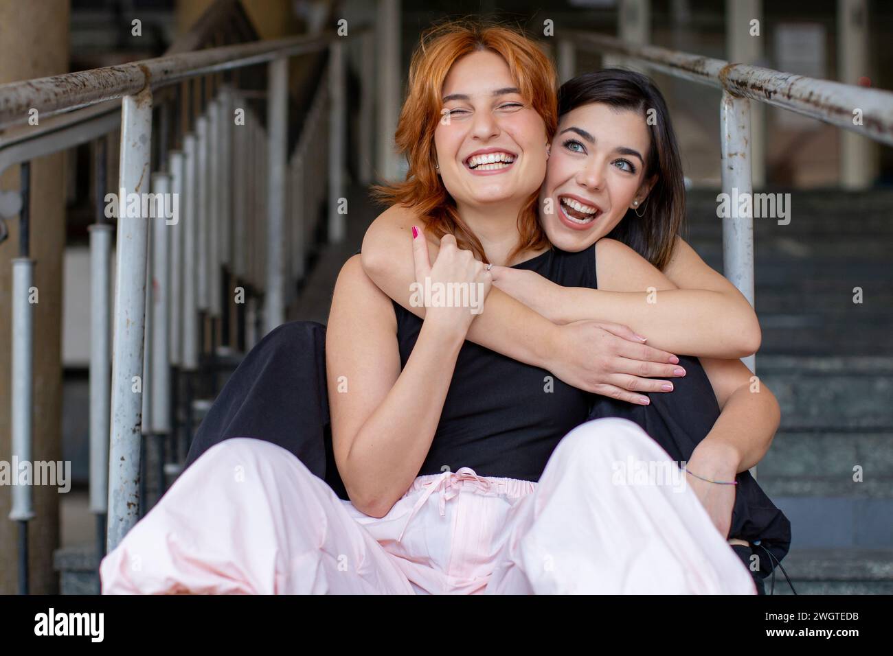 two young women sitting and hugging Stock Photo - Alamy