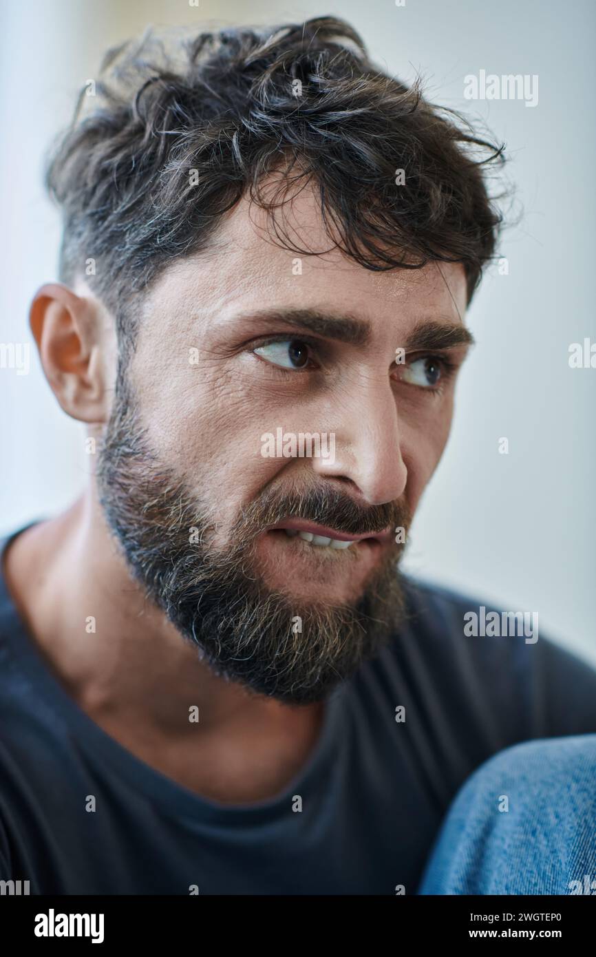 ill traumatized man with beard biting his lips during depressive ...