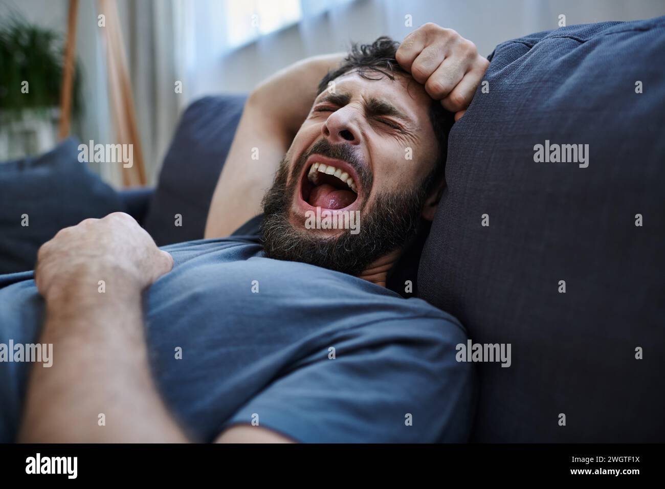 desperate depressed man in homewear on sofa screaming during breakdown ...